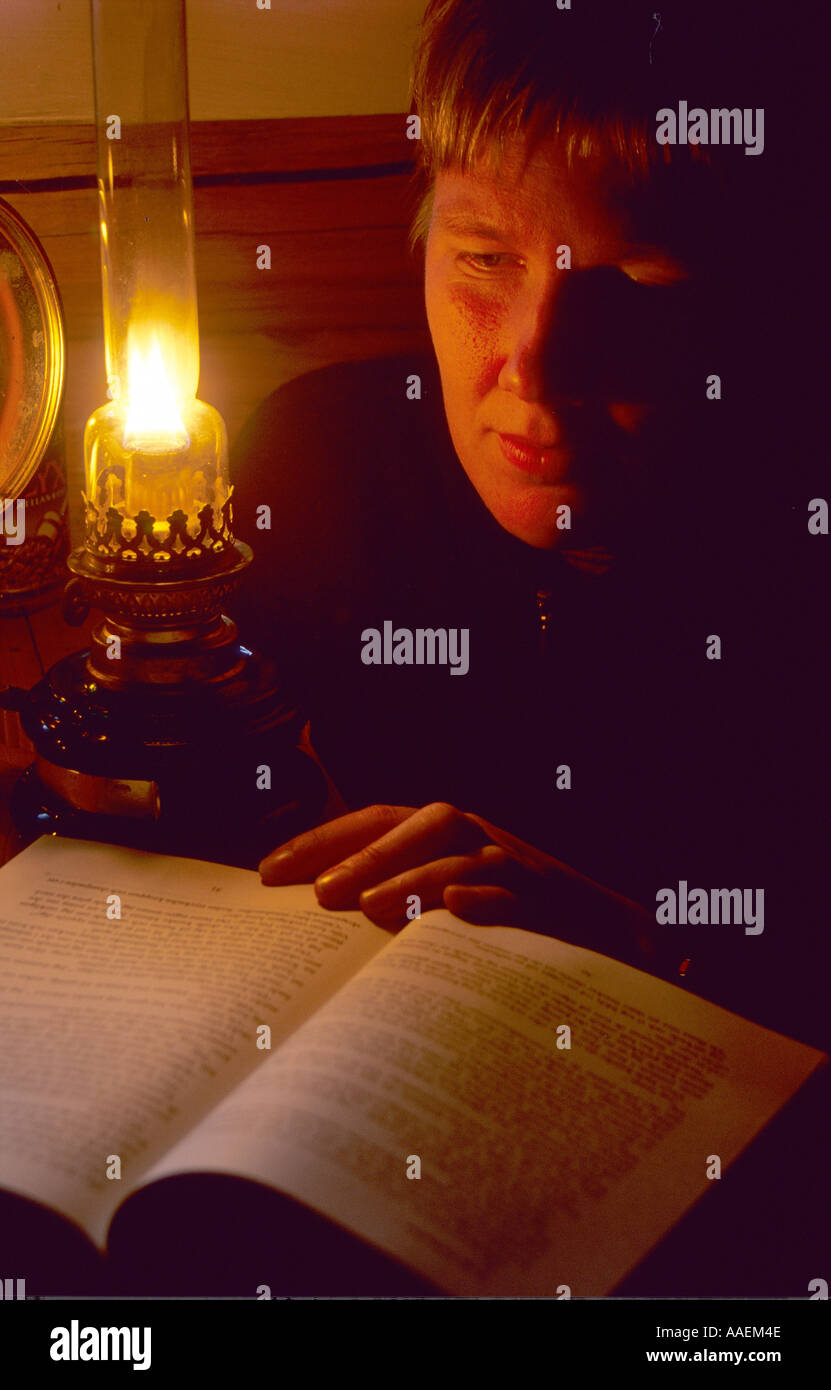 Woman reading book in the light of a kerosene lamp Stock Photo - Alamy