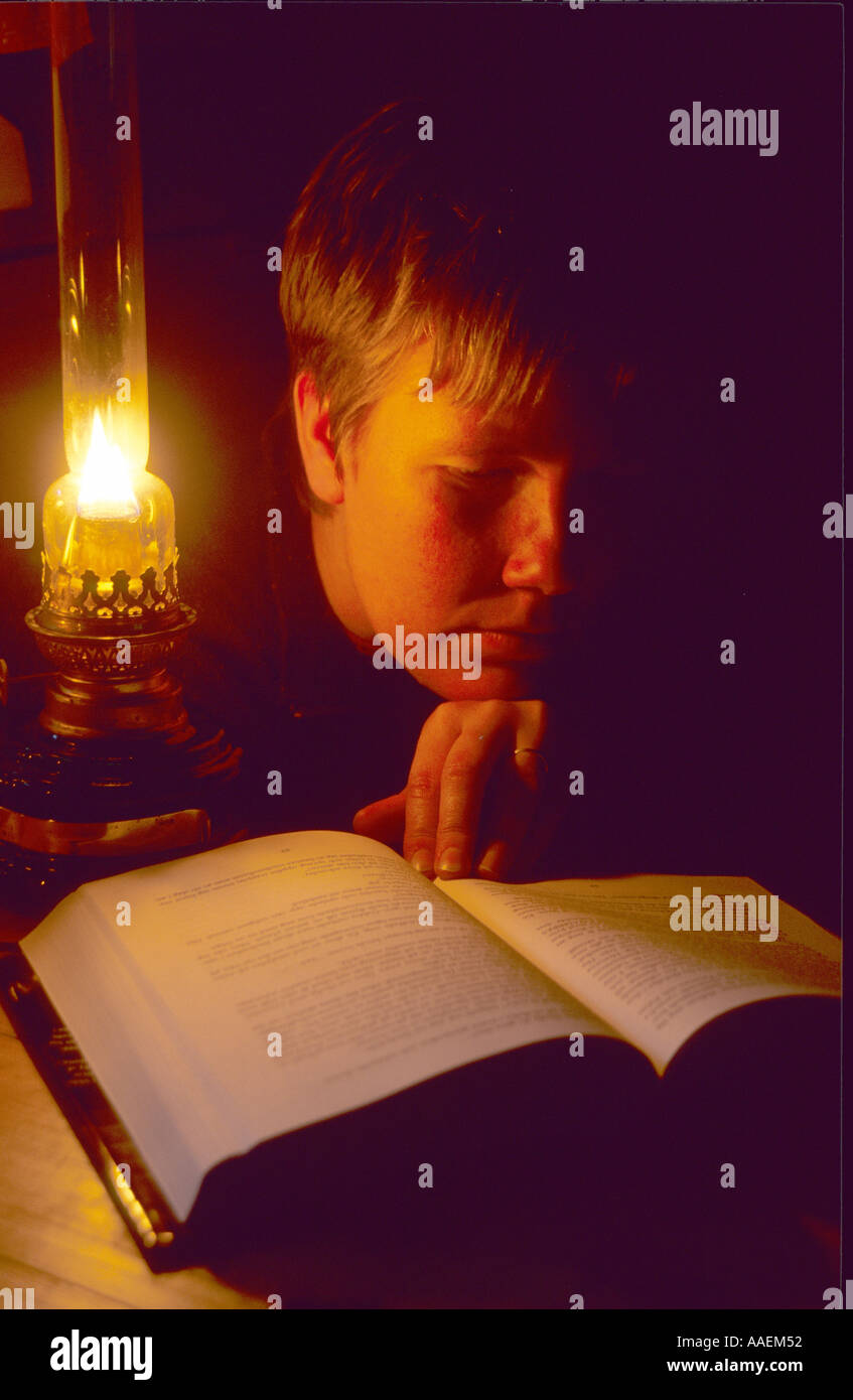 Woman reading book in the light of a kerosene lamp Stock Photo - Alamy