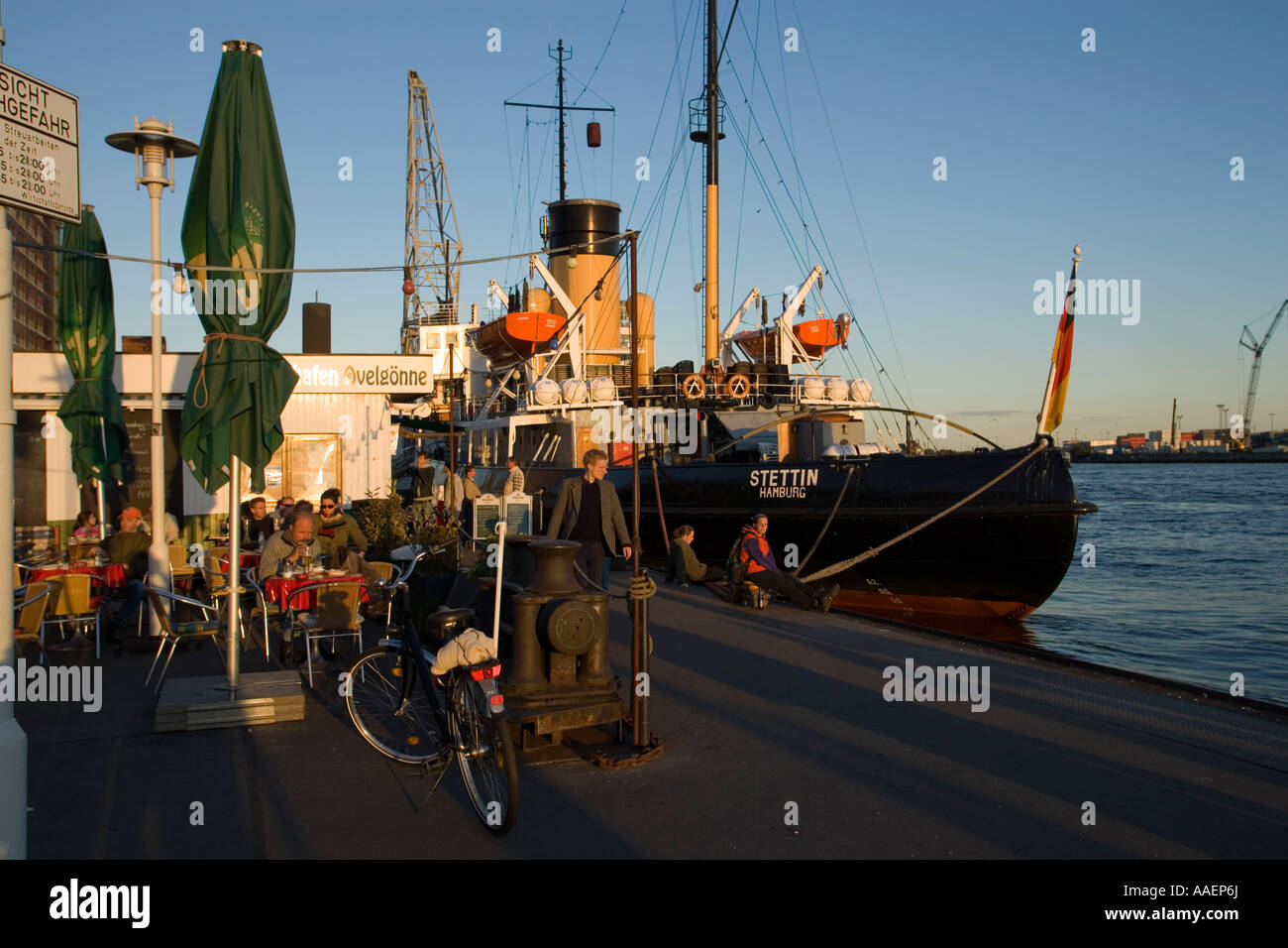 People sitting at pier of Museumshafen near the steam icebreaker ...