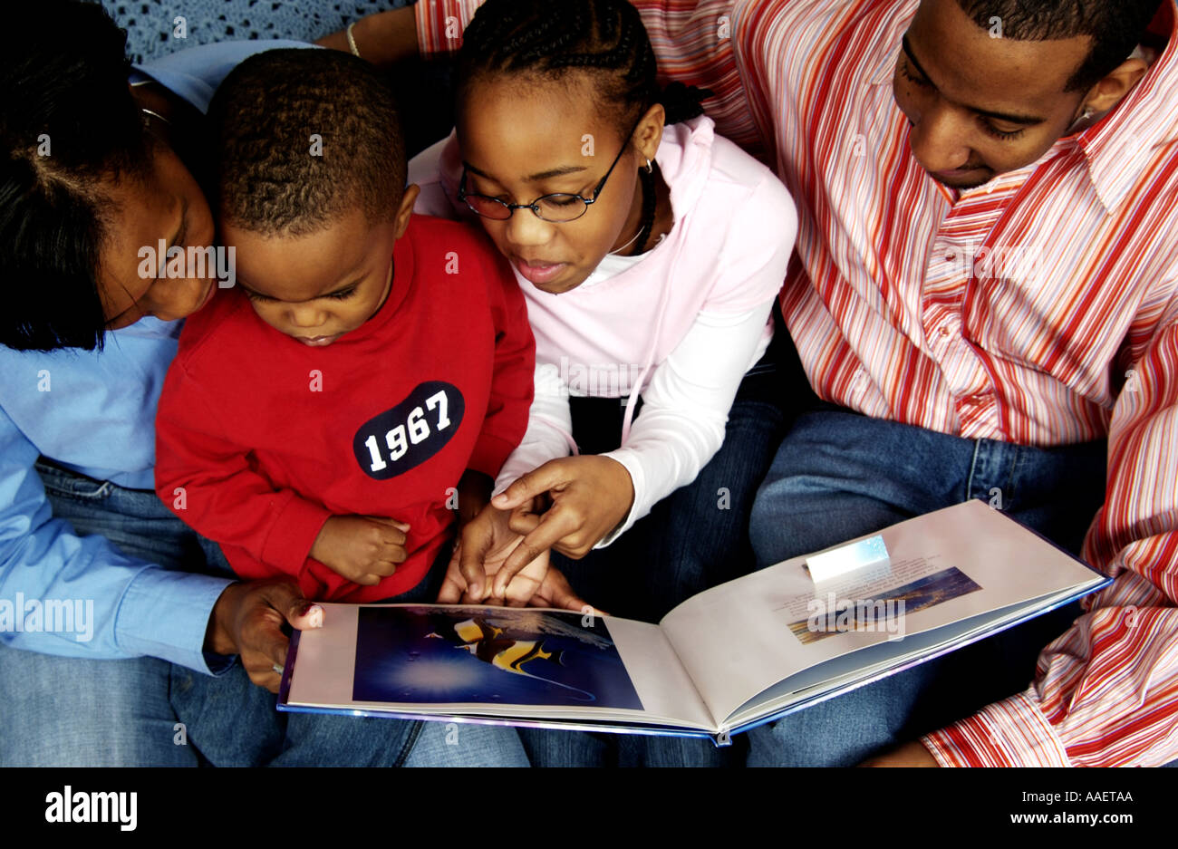 Parents reading a book with kids Stock Photo - Alamy