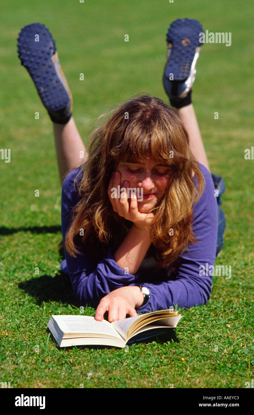 Girl on lawn reading book Stock Photo - Alamy