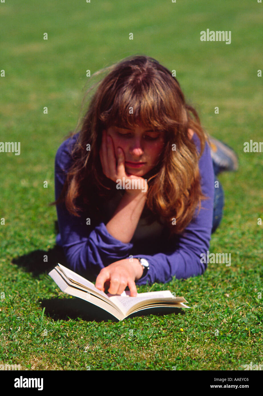 Girl on lawn reading book Stock Photo - Alamy