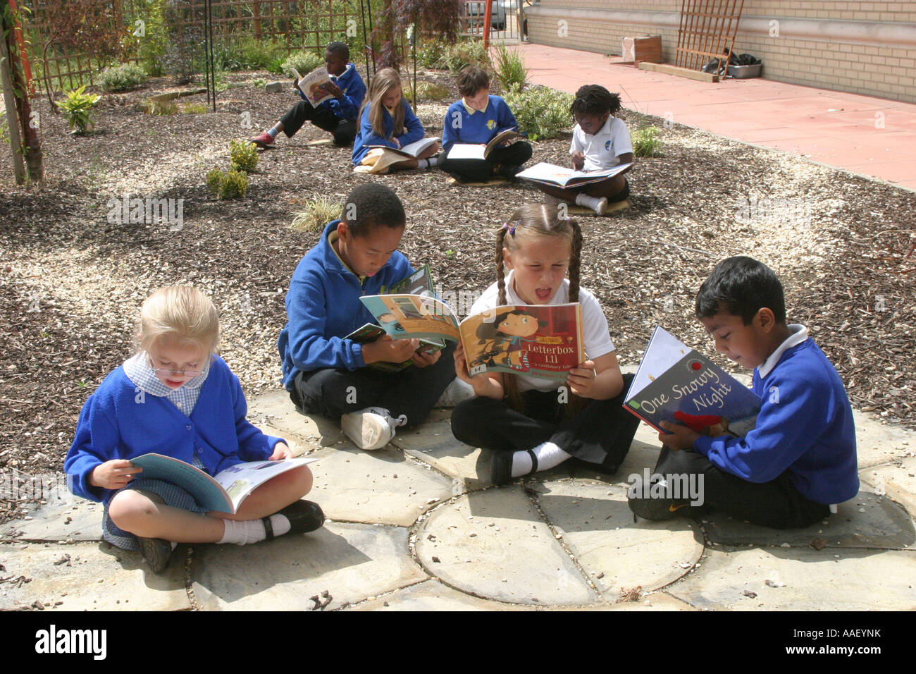 Primary school children in playground reading books Stock Photo - Alamy