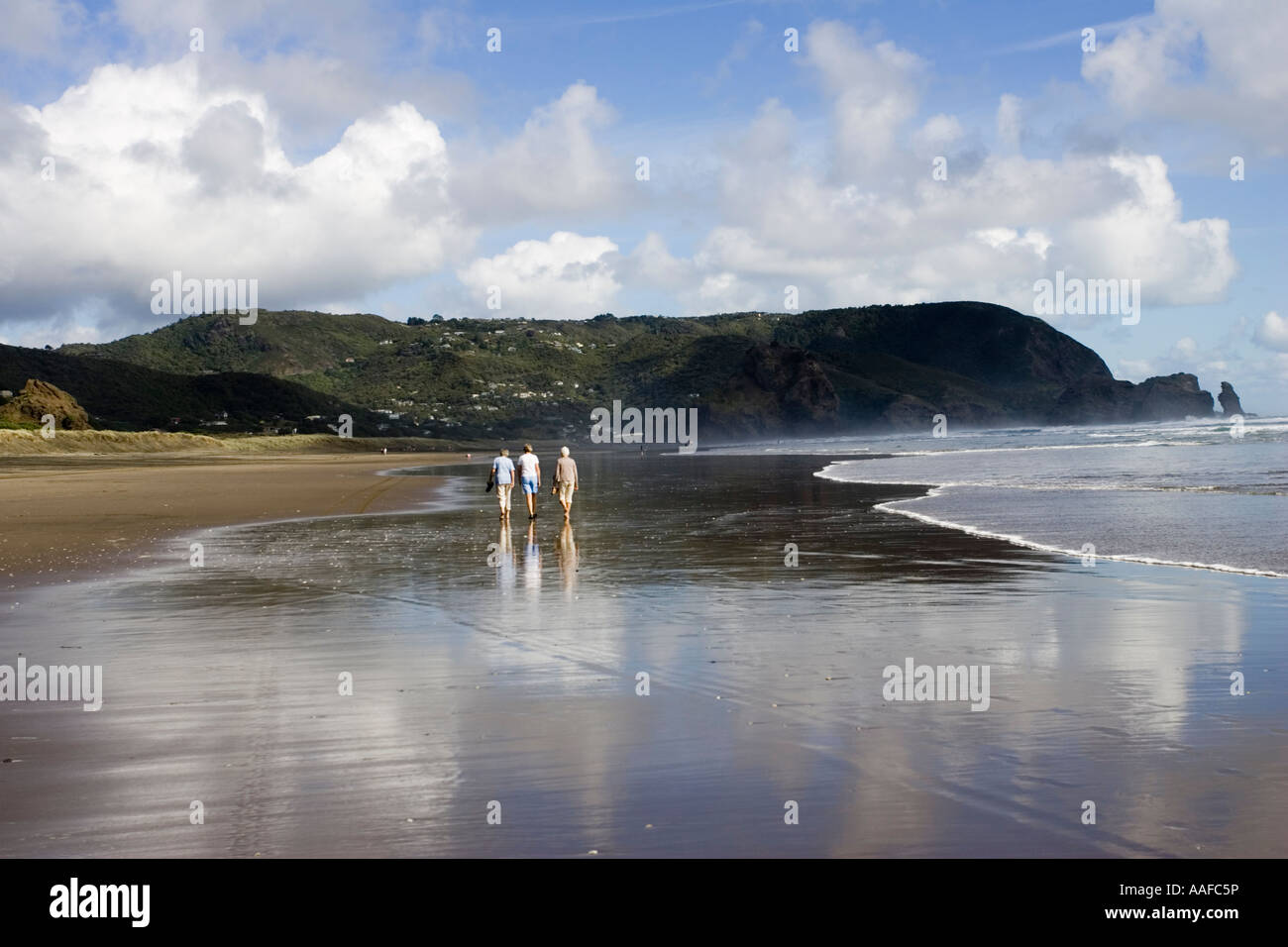 Three women walking along Tiha beach at low tide Waitakere Ranges ...