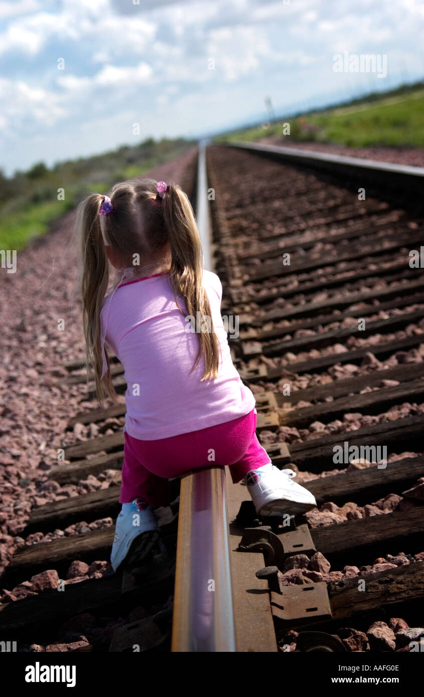 Girl sitting on railroad tracks Stock Photo - Alamy