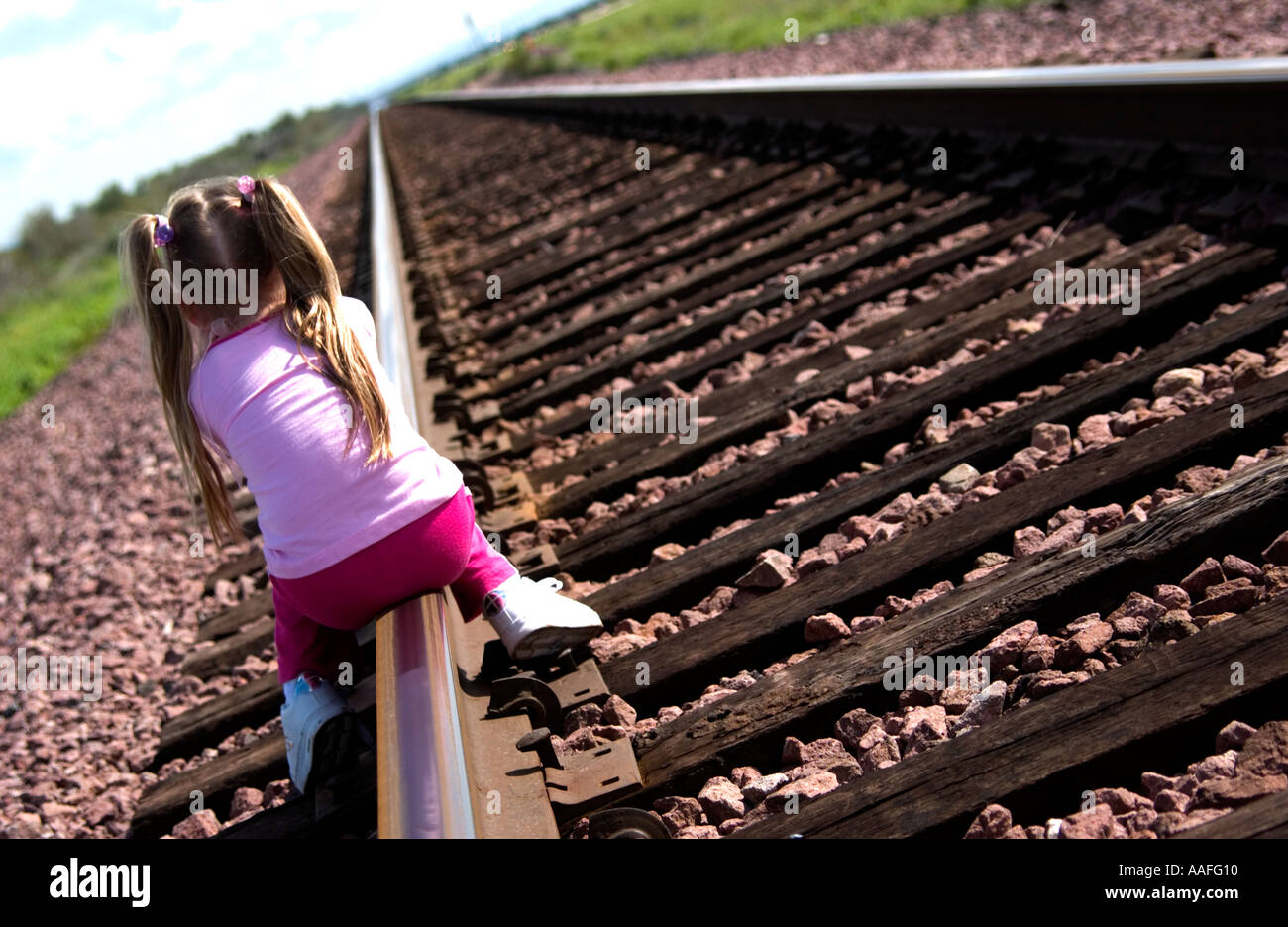 Girl sitting on railroad tracks Stock Photo - Alamy