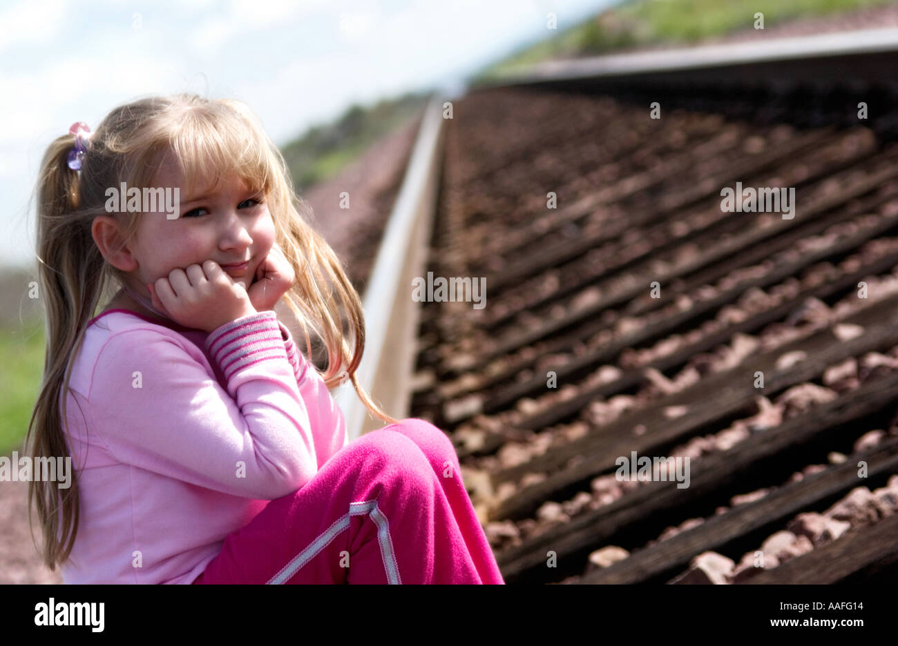 Girl sitting on railroad tracks Stock Photo - Alamy