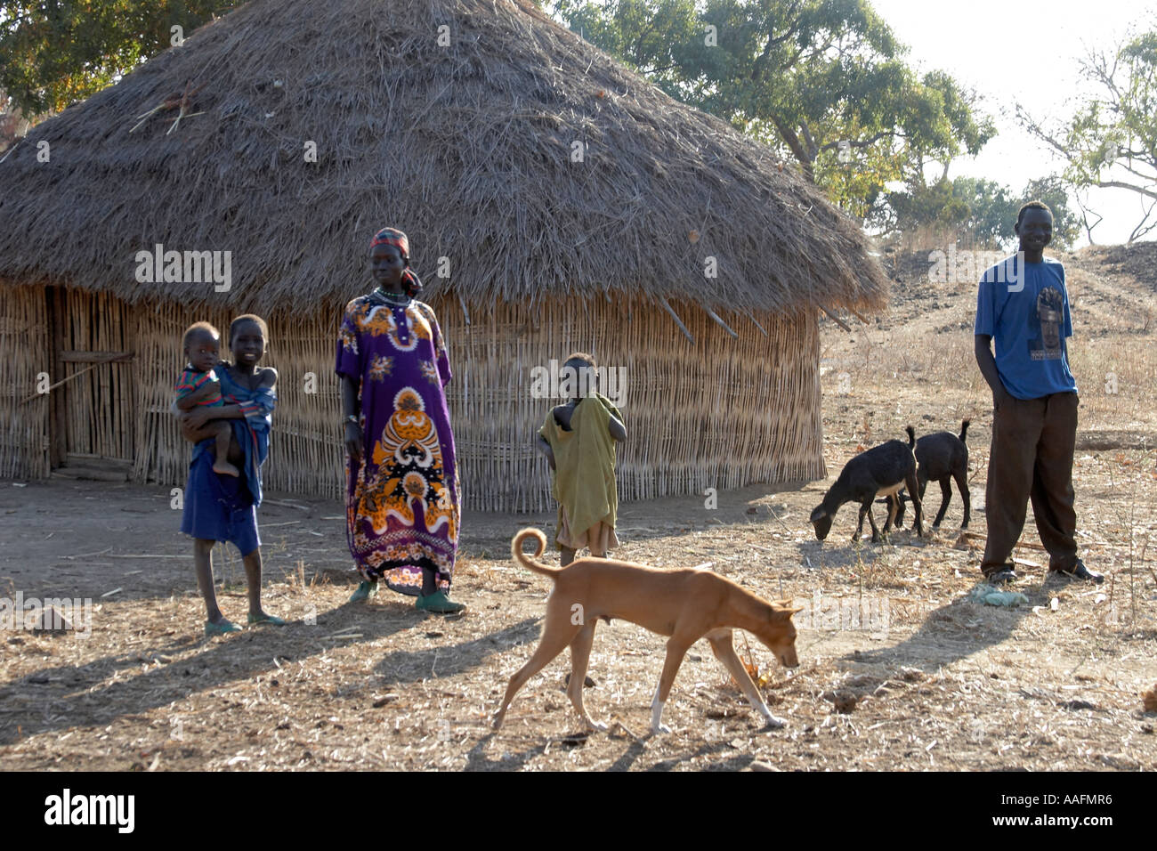 Family baby and dogs with round hut house in Boka village near Deletti ...