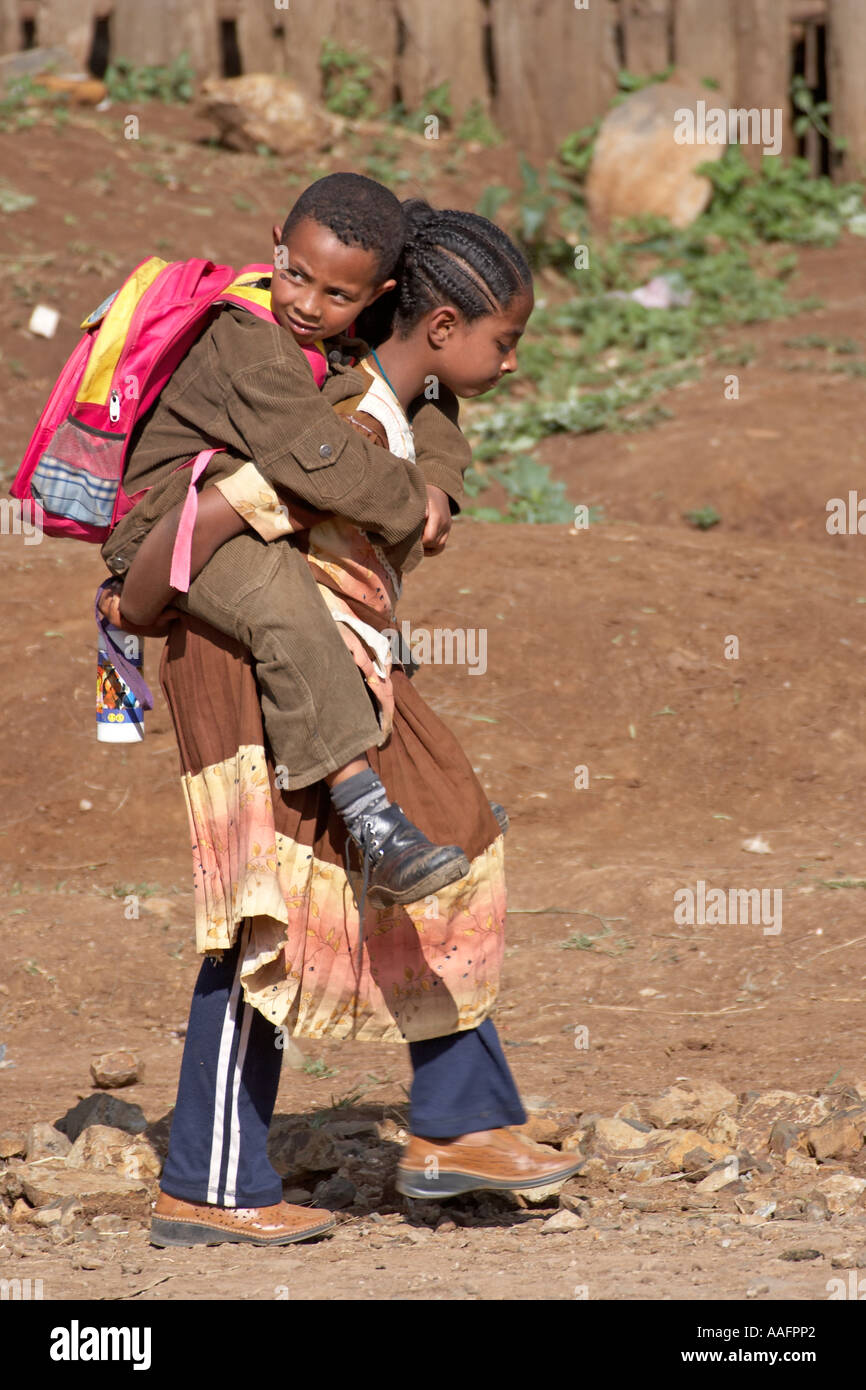 Young girl carrying her brother on her back piggyback in Bure Ethiopa ...