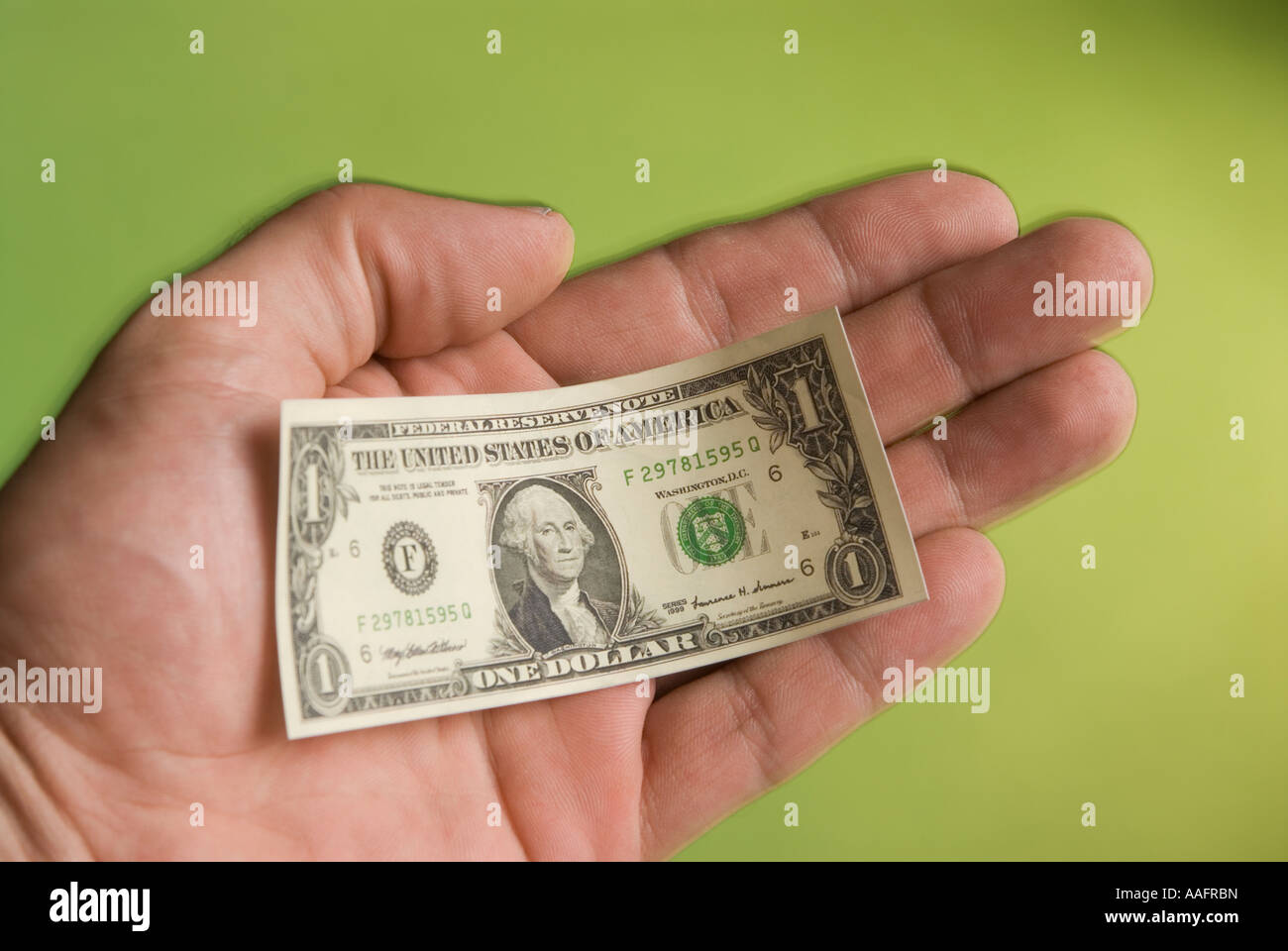 a hand holding a miniature United States one dollar bill depicting the ...