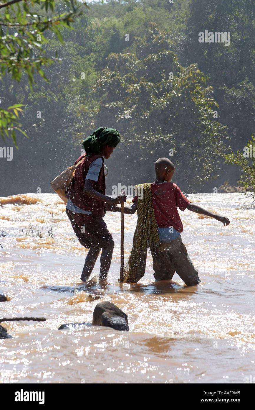 People wading or fording a dangerous river at the top of a waterfall ...