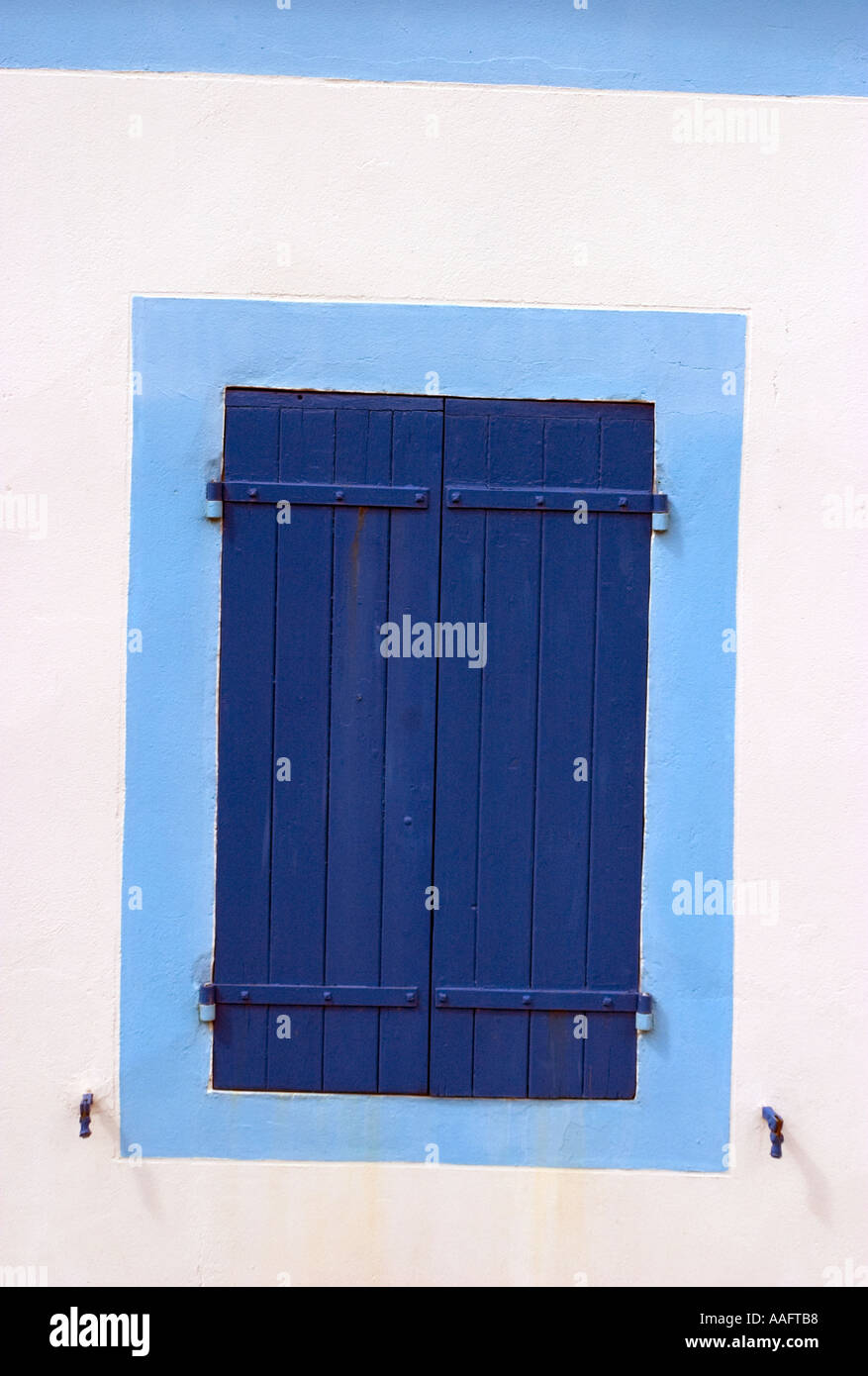 wall frontage of house with blue and withe window with closed shutters ...