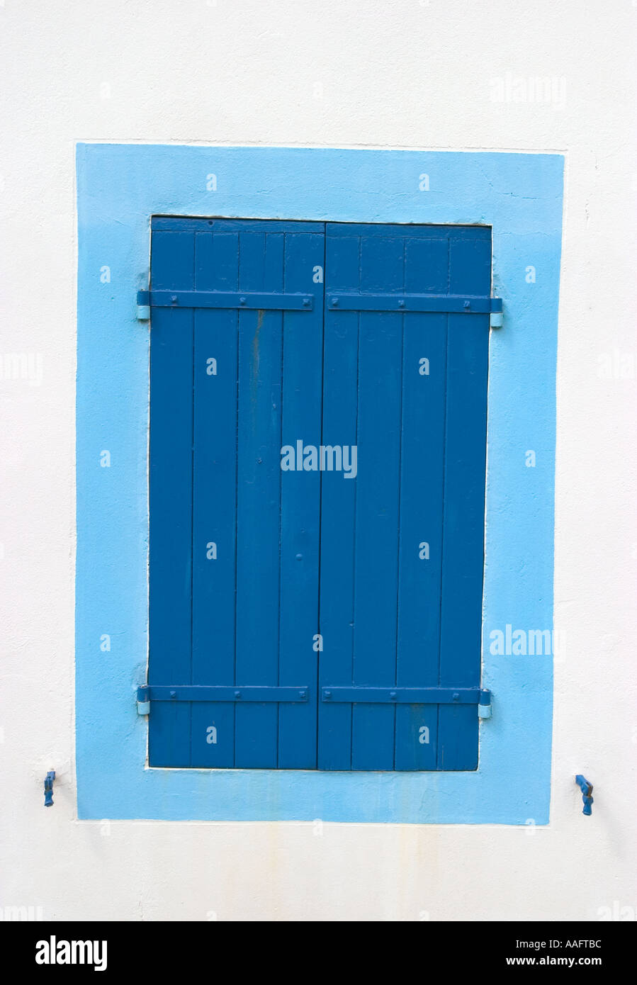 wall frontage of house with blue and withe window with closed shutters ...