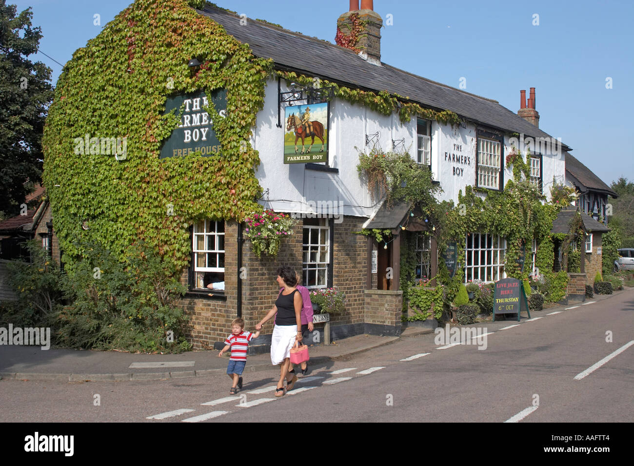Mother and child walking outside The Farmer s Boy pub on a summer day ...