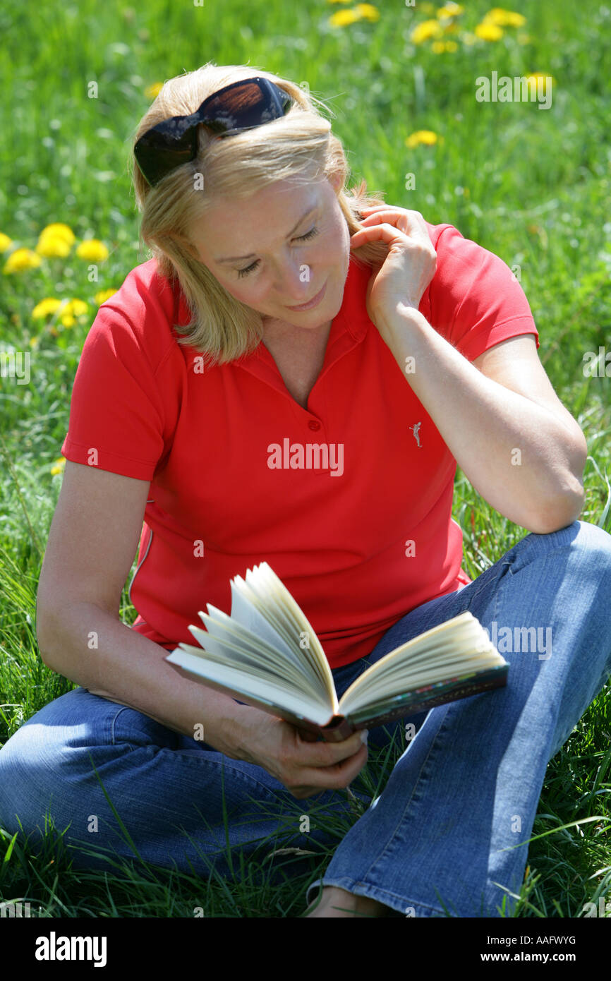 Mature woman reading book outside in garden Stock Photo - Alamy