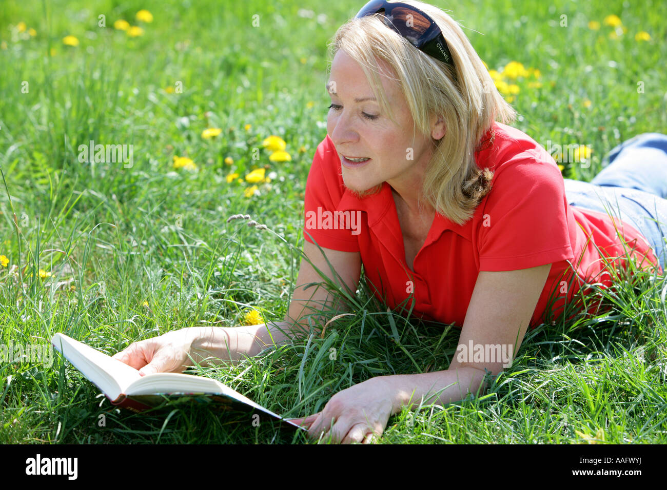 Mature woman reading book outside in garden Stock Photo - Alamy