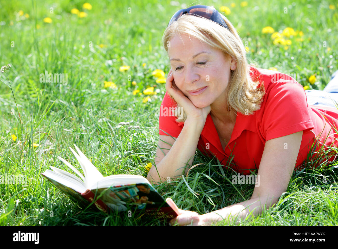 Mature woman reading book outside in garden Stock Photo - Alamy
