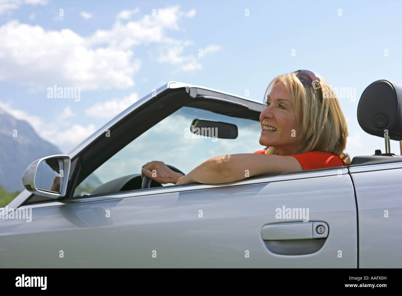 A senior woman driving cabriolet sportscar with roof down Stock Photo ...