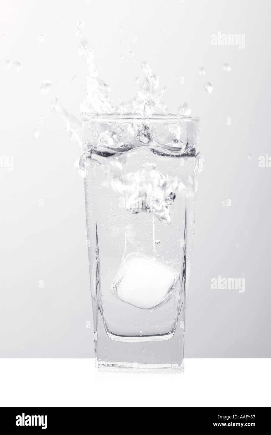 Ice cube being dropped into glass of water Stock Photo - Alamy