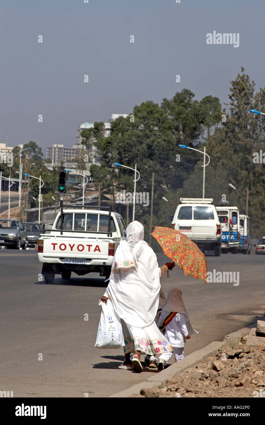 Woman with shawl and umbrella shielding two children from sun Addis ...