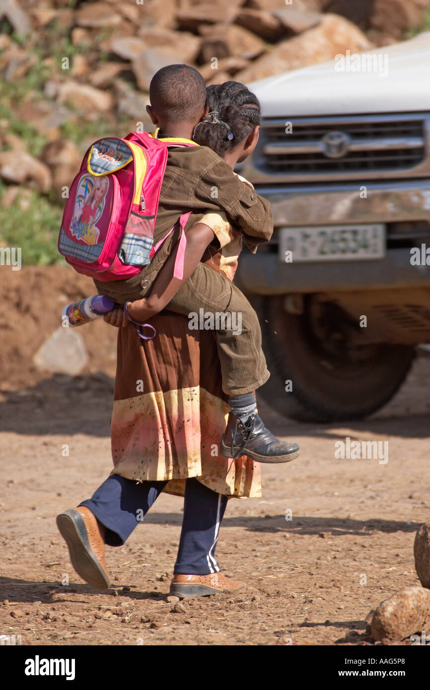 Young girl carrying her brother on her back piggyback in Bure Ethiopa ...
