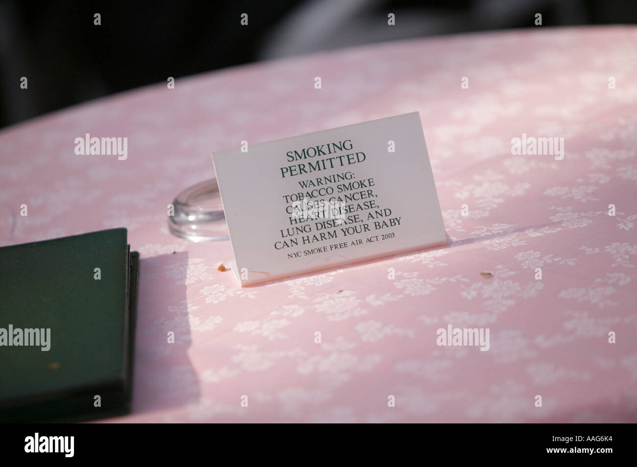 A Smoking Permitted sign carrying a health warning stands on an outdoor ...