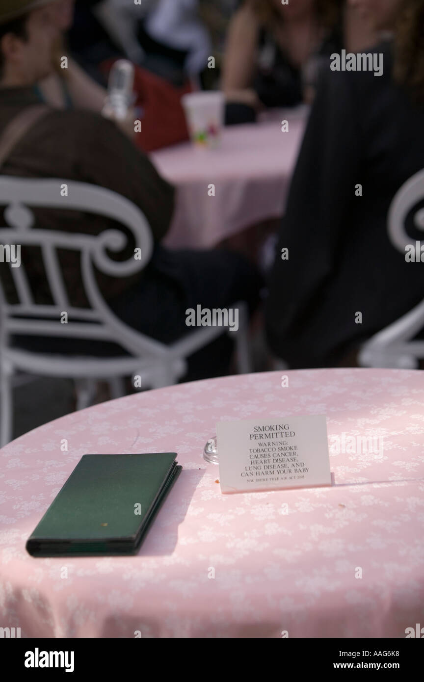 A Smoking Permitted sign carrying a health warning stands on an outdoor ...