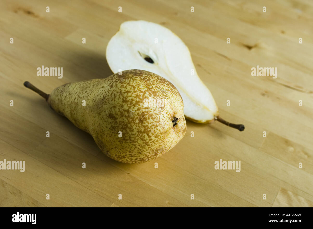 one whole and one halved pear on a wooden table Stock Photo - Alamy