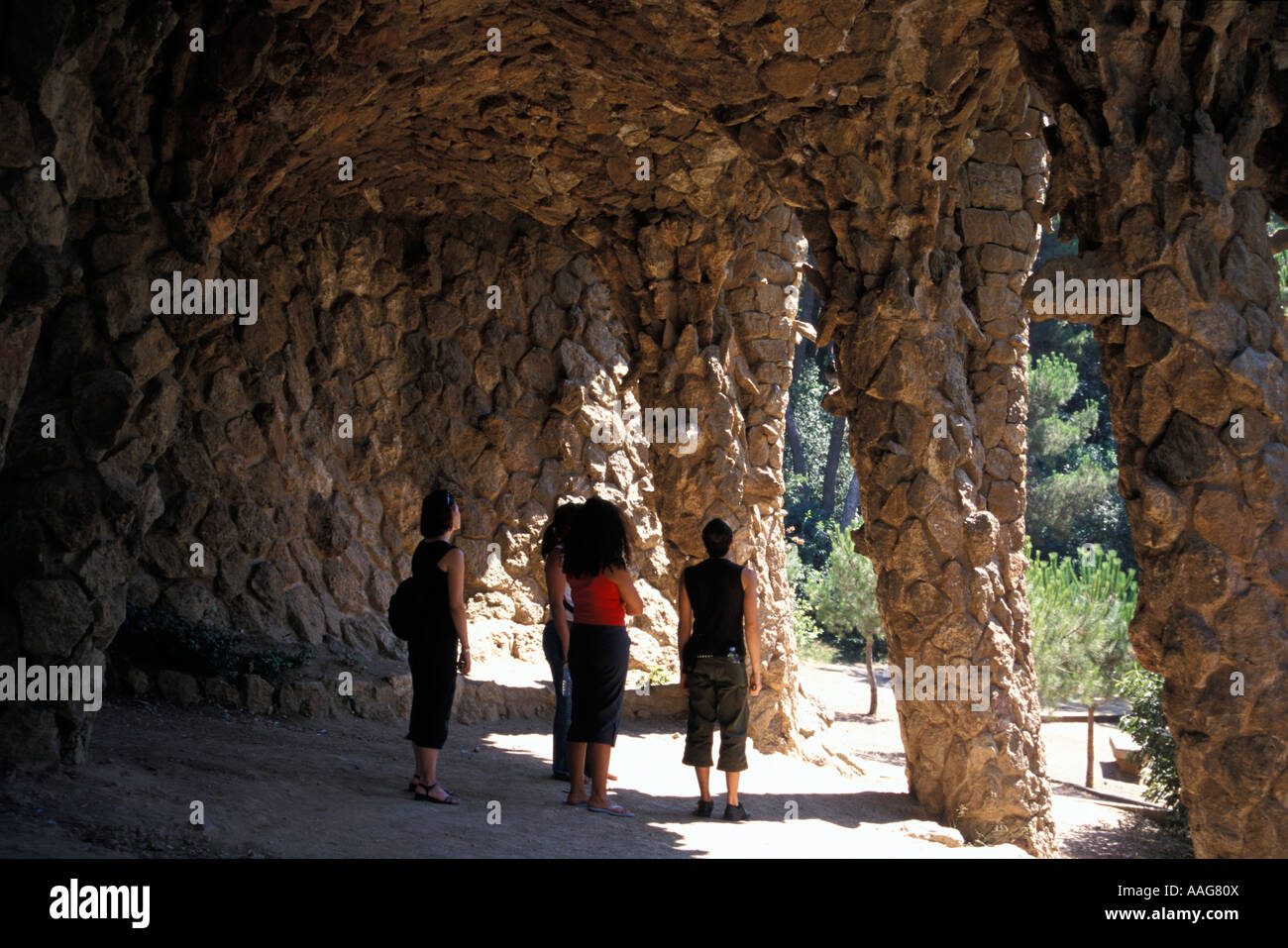 People visiting colonaded pathway Park Guell designed by Antoni Gaudi ...