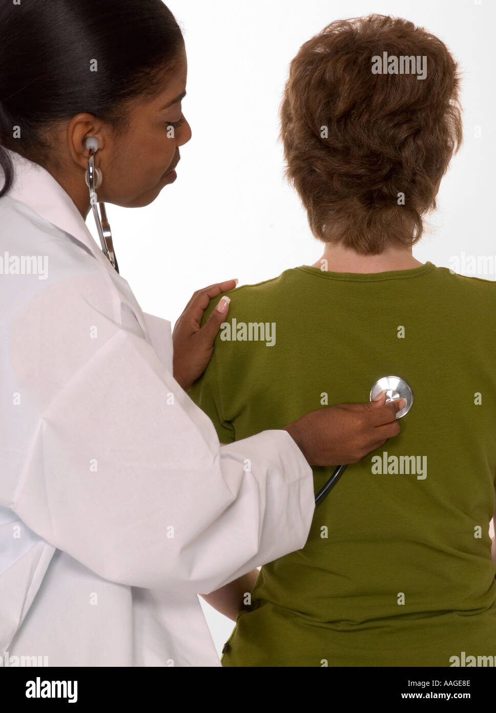 African American doctor using stethoscope to examine Caucasian female ...