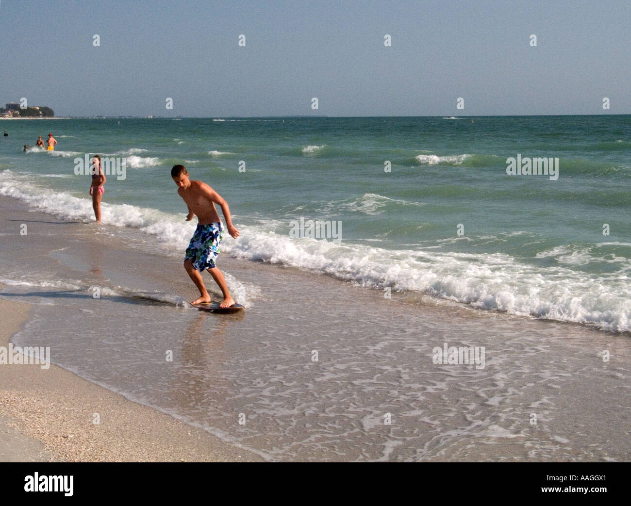 A young man skimming across the sand on a board Stock Photo - Alamy