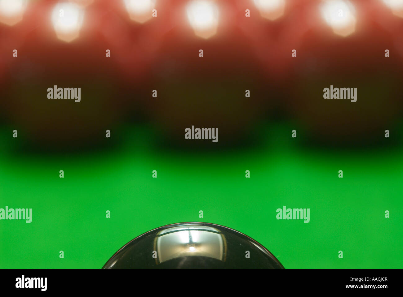 Black ball on the green baize of a snooker table with the reds racked ...