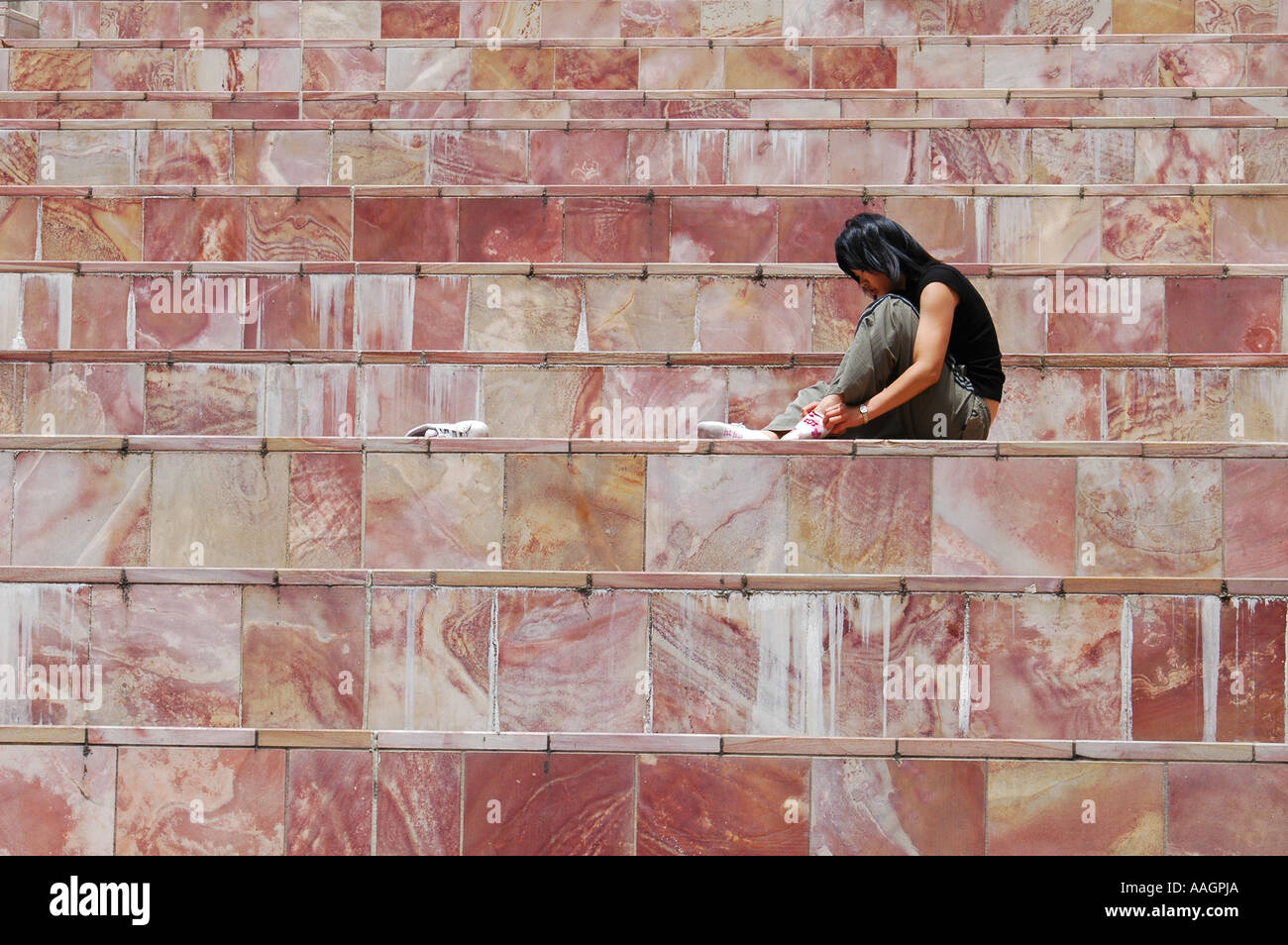 Woman sitting on steps putting on her socks and shoes Stock Photo - Alamy