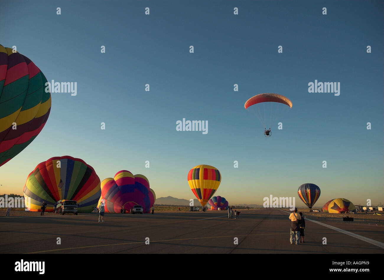Hot Air balloons being inflated on runway with other craft in the air ...