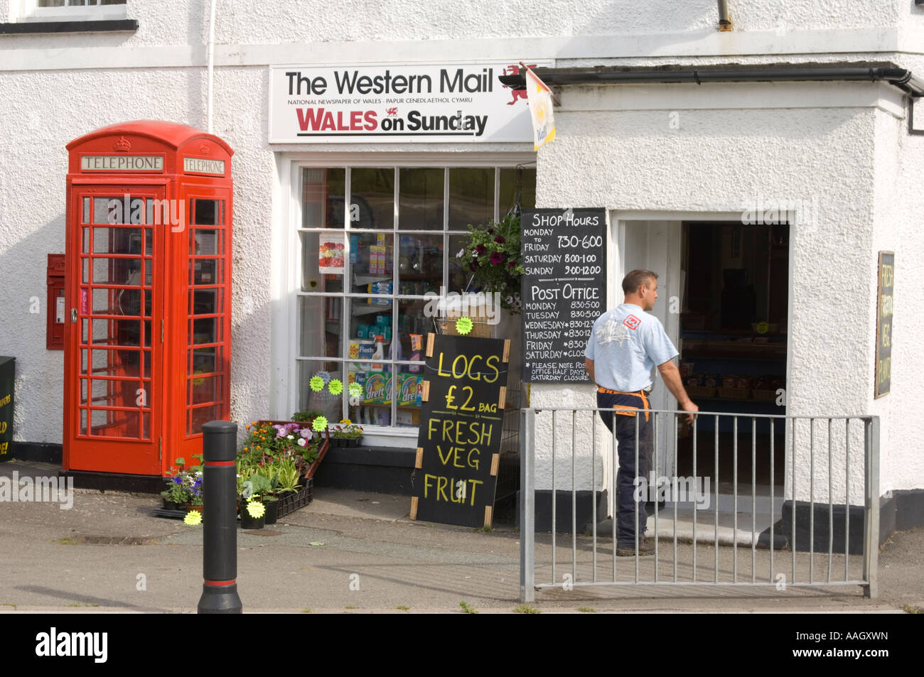 red telephone box and man walking into Llanwnen post office and local ...