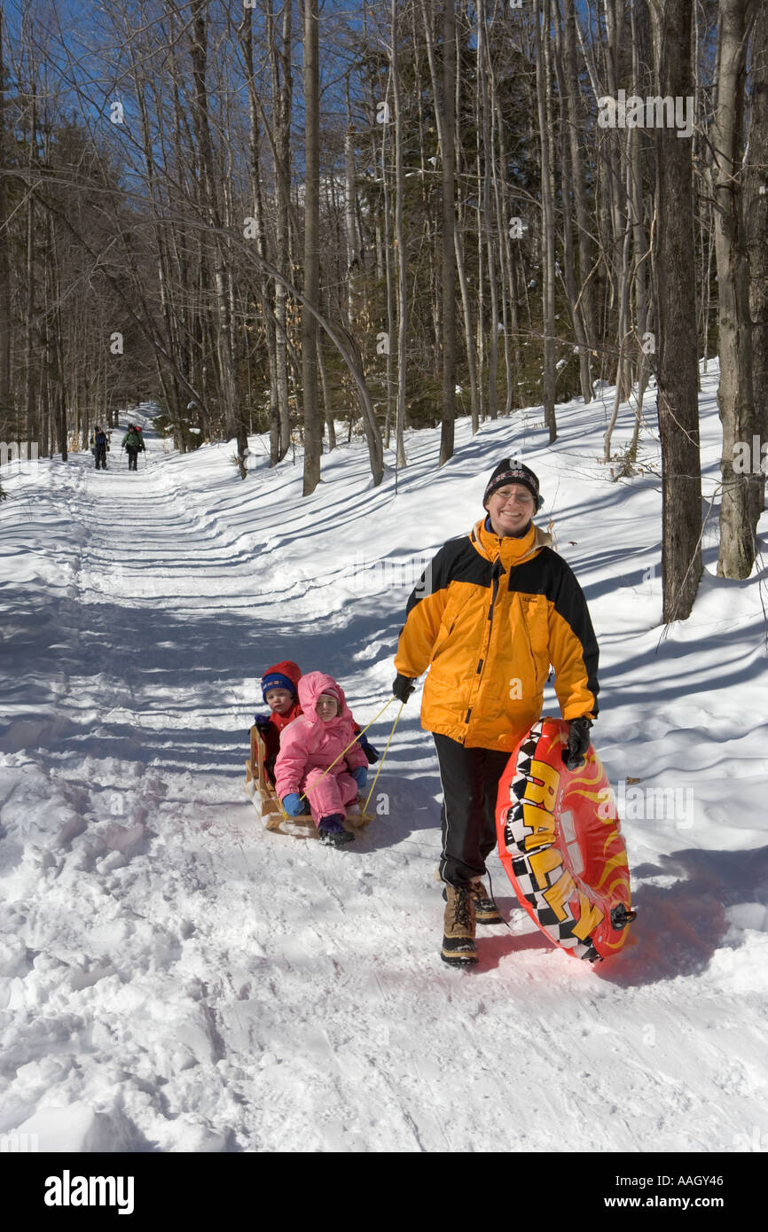 Mom pulling kids on sled through snow Stock Photo - Alamy
