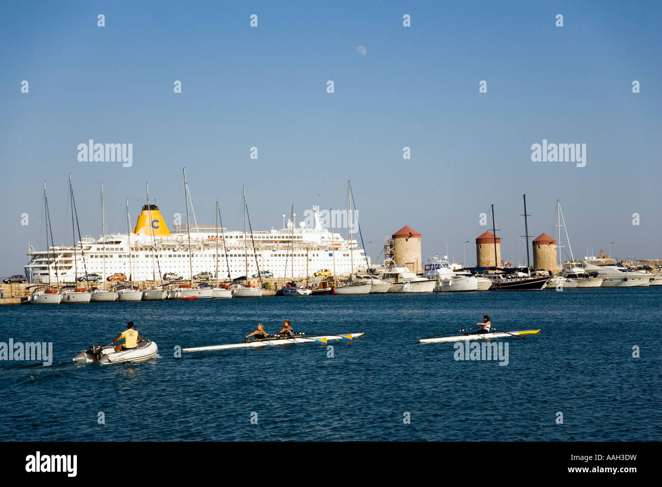 eople rowing in the Mandraki harbour ailing boats and windmills on mole ...