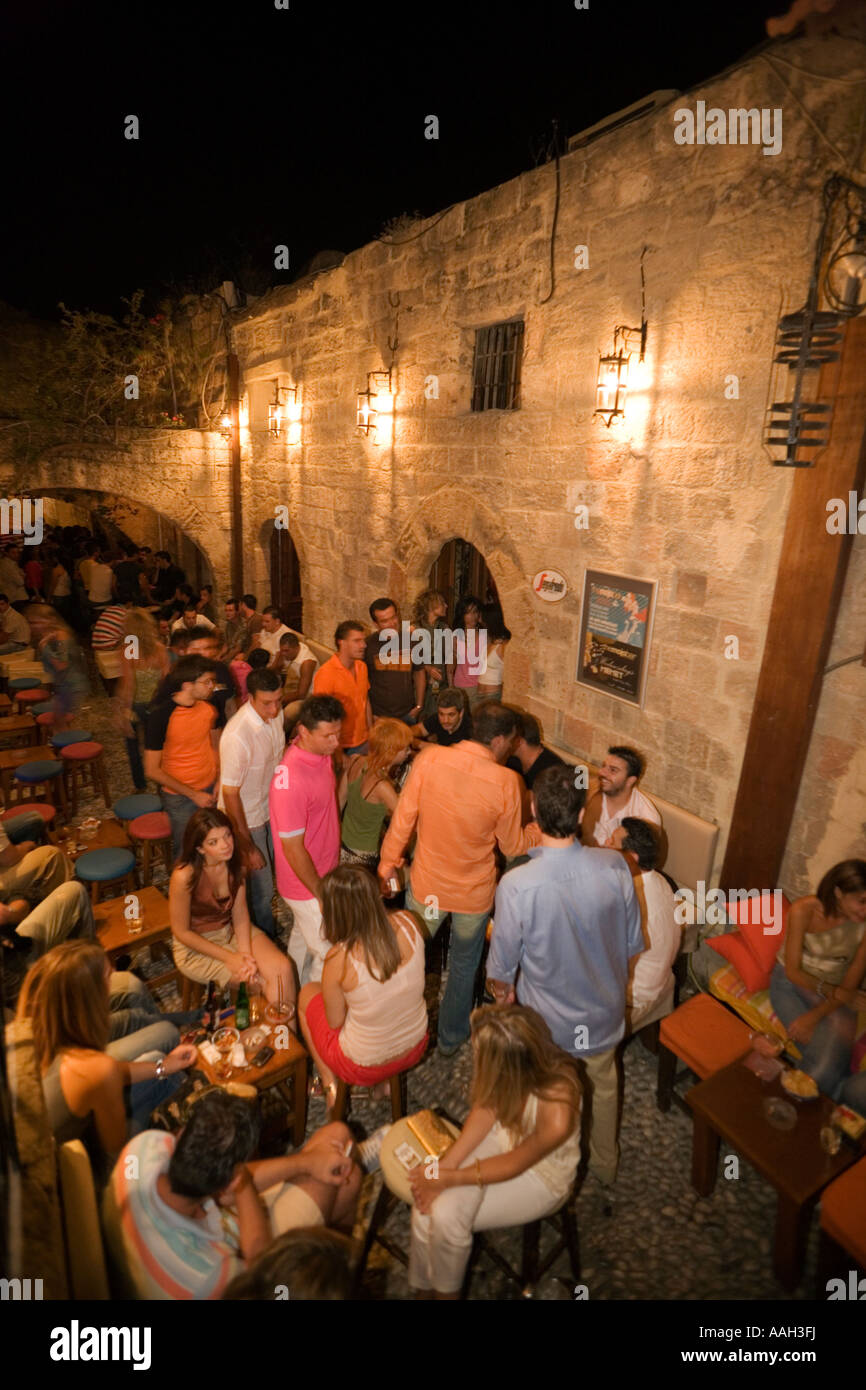 People sitting in outdoor areas of several bars of old town Rhodes Town ...