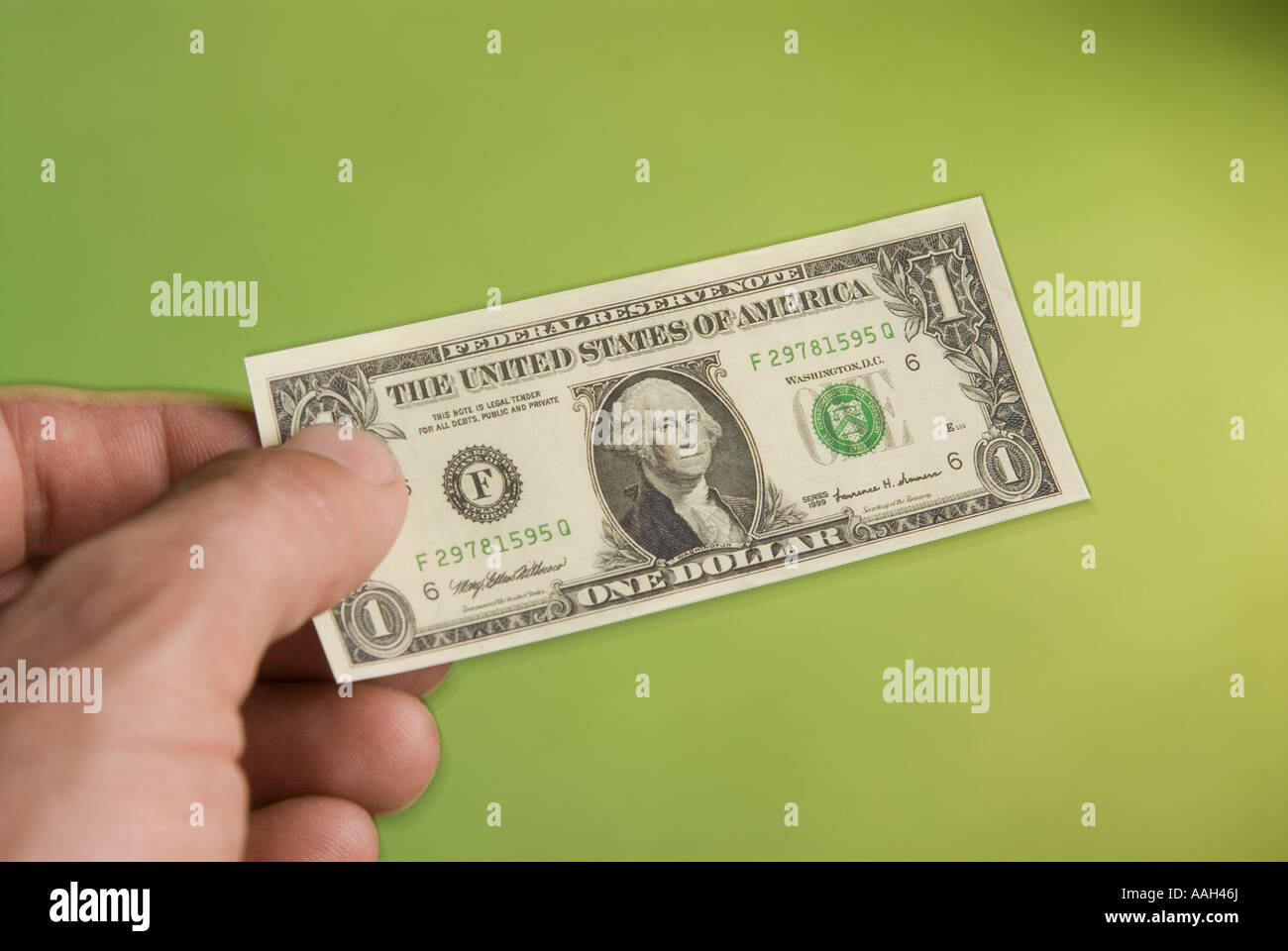a hand holding a miniature United States one dollar bill depicting the ...