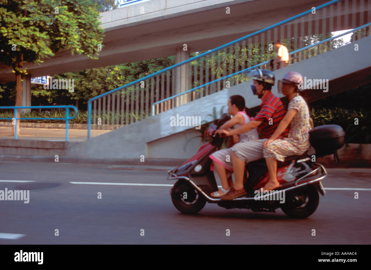 Chinese family rides three people on a scooter in Guangzhou mainland ...