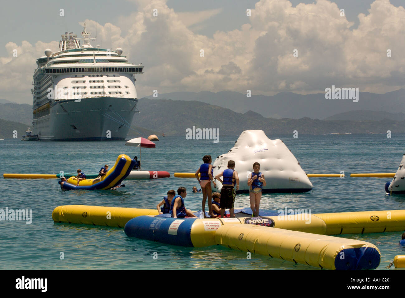 Children playing on inflatable toys in waters along beach with cruise ...