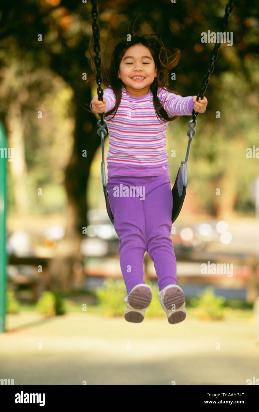 Girl 4 5 swinging on swing smiling portrait Stock Photo - Alamy