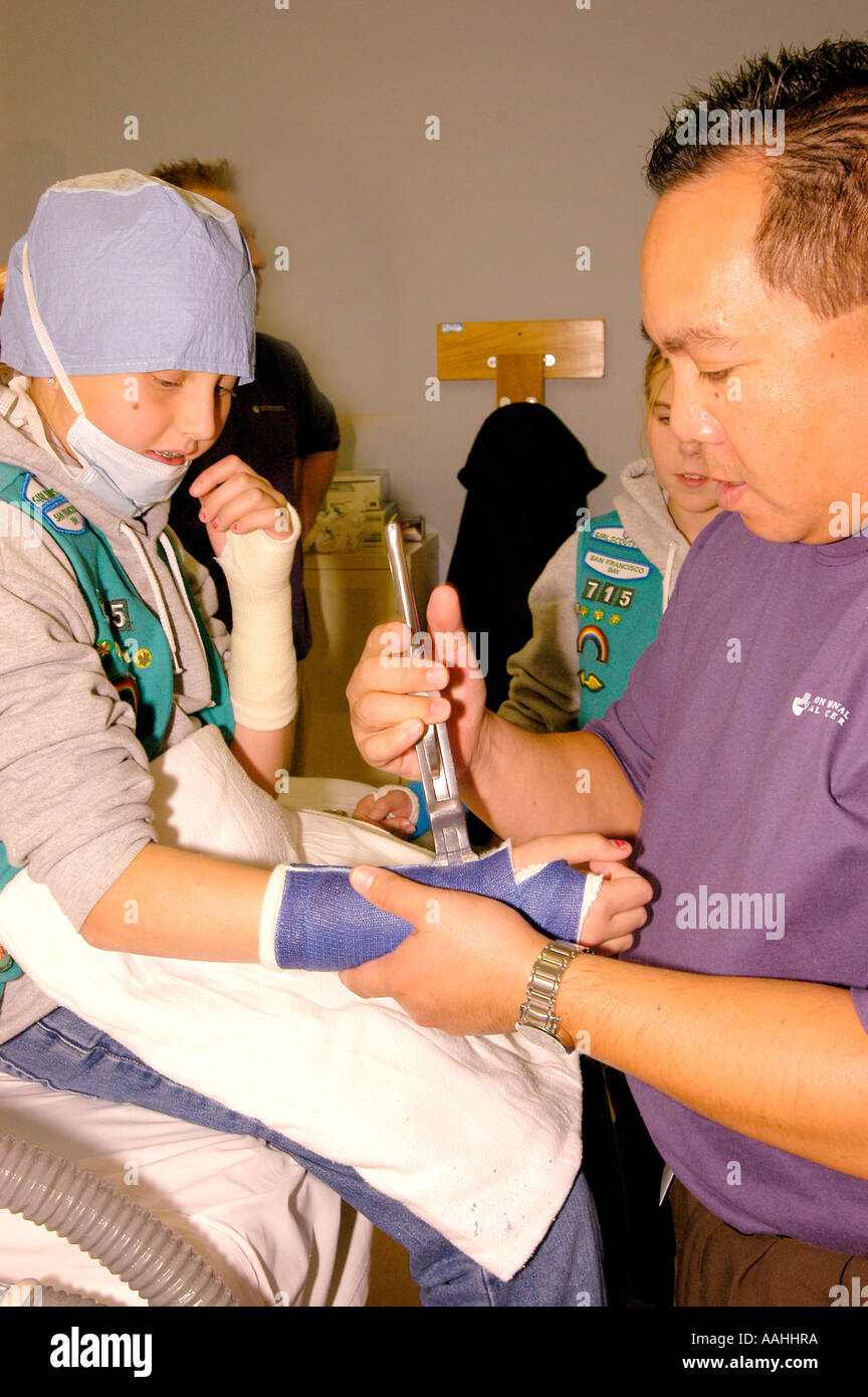 Nurse on hospital staff removing a fake cast from a young girl wearing ...