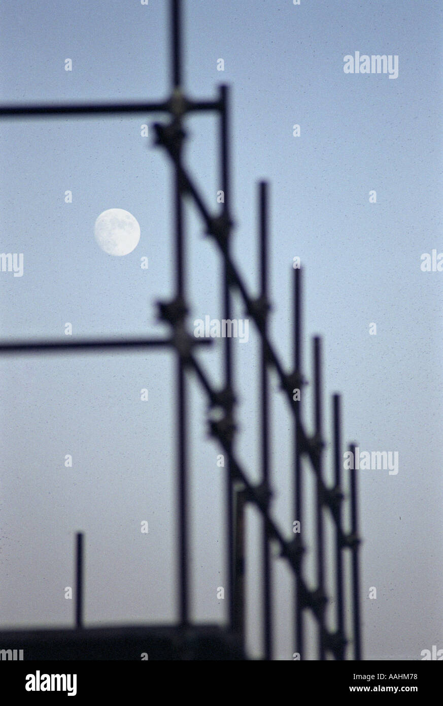 the moon through scaffolding with birds flying Stock Photo - Alamy