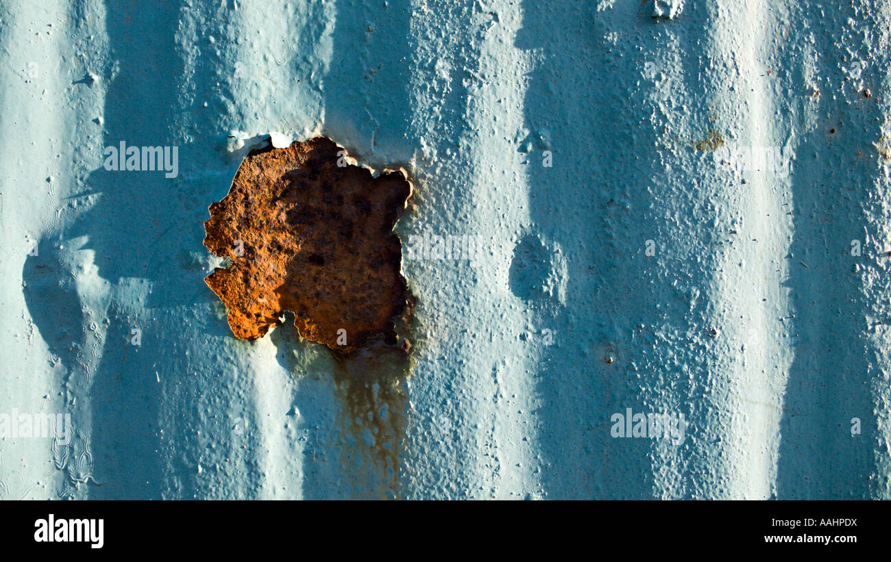 A rusty patch in a piece of old painted corrugated iron Stock Photo - Alamy
