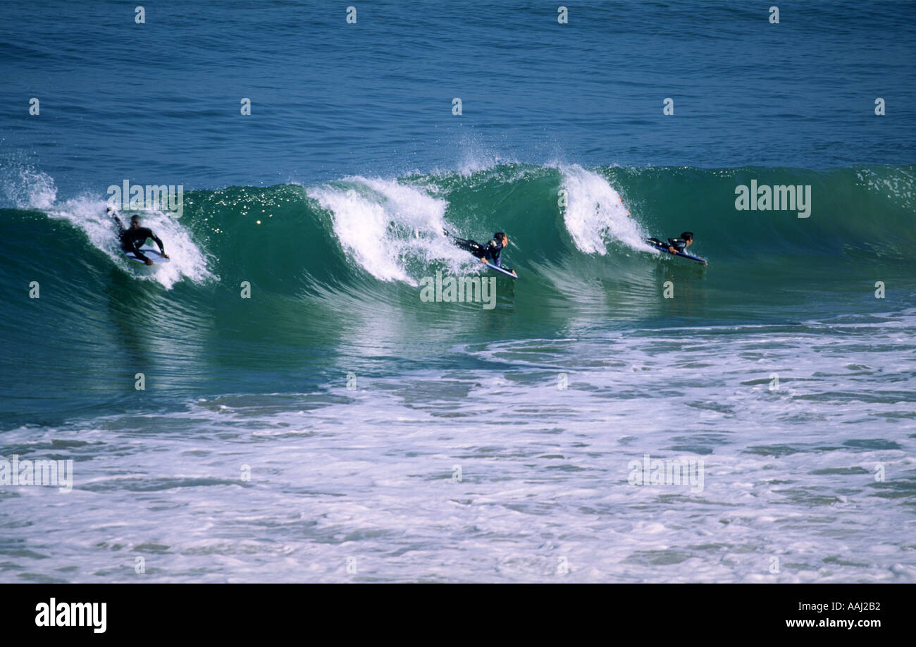 three surfers in a wave Stock Photo - Alamy