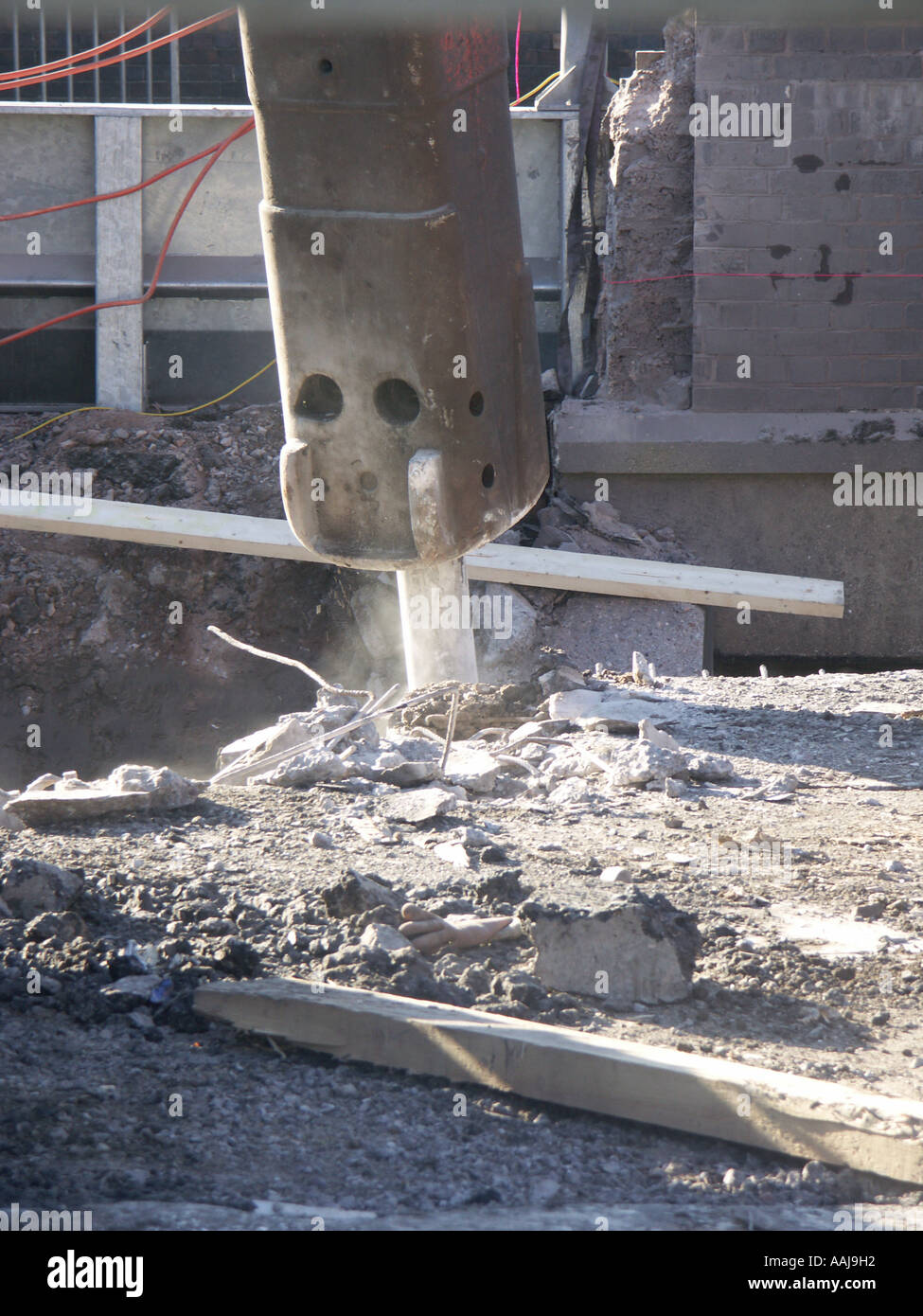 Breaking up road surface with percussive hammer attachment on a digger ...