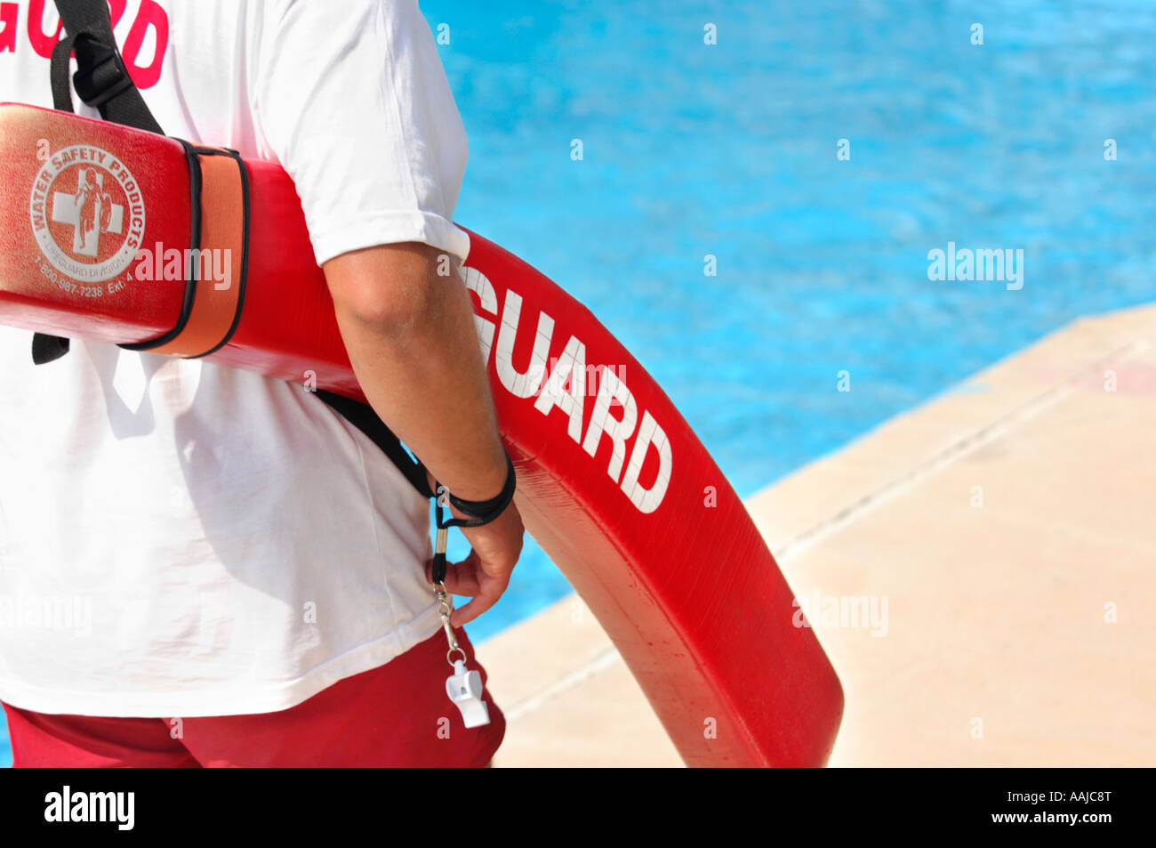 Life guard walking along a pool in a water park with a life saving buoy ...
