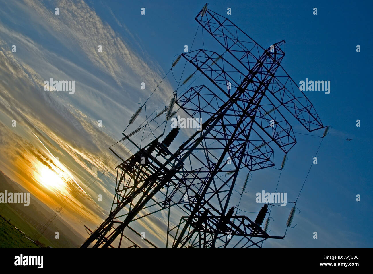Sun setting behind electricity pylon Stock Photo - Alamy