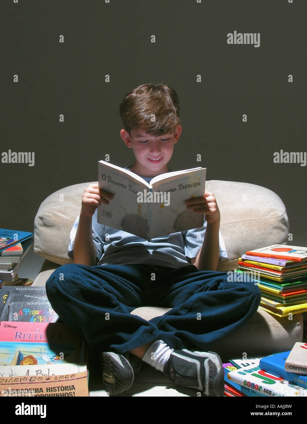 Boy (6-7) surrounded by stacked books, reading one, portrait Stock ...